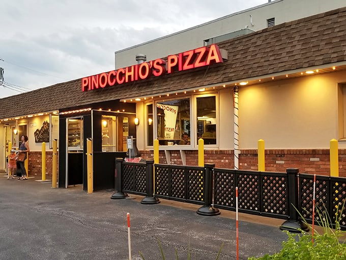 That iconic red neon sign beckons like a lighthouse for the pizza-starved, promising salvation in the form of perfectly melted cheese.