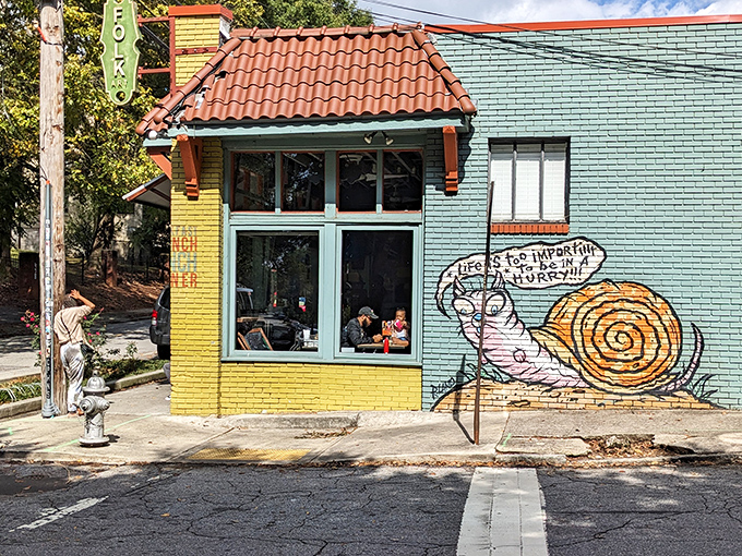 The teal and yellow exterior of Folk Art Restaurant stands out like a cheerful beacon in Inman Park, complete with a philosophical snail mural that speaks breakfast truths.
