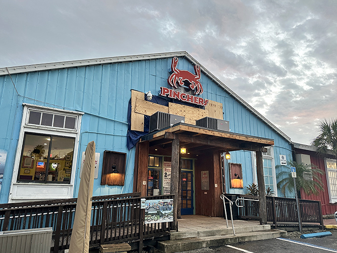 The bright blue exterior of Pinchers stands like a seafood beacon against the Florida sky, promising treasures from the deep within its weathered wooden walls.