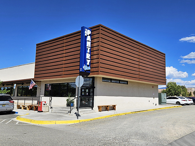 From another angle, the modern wood-paneled exterior of The Pantry Dos shows off its contemporary design while that iconic blue sign promises traditional New Mexican flavors inside.