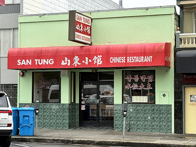 The unassuming mint-green exterior and bright red awning of San Tung – proof that culinary greatness often hides behind the most modest facades.