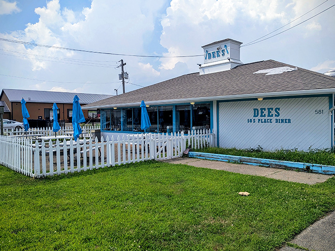 The blue and white exterior of Dee's 50's Place Diner promises nostalgic comfort, complete with a picket fence that practically whispers "come hungry, leave happy."