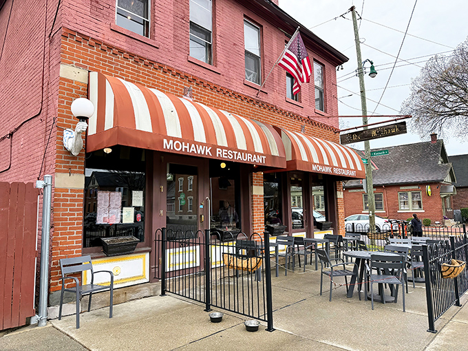 The iconic red brick exterior of The Old Mohawk, with its distinctive striped awnings, stands as a beacon of comfort food in Columbus' German Village.