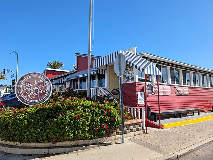 The iconic red exterior with blue-and-white striped awnings stands like a culinary lighthouse on PCH, beckoning hungry travelers with promises of comfort food perfection.