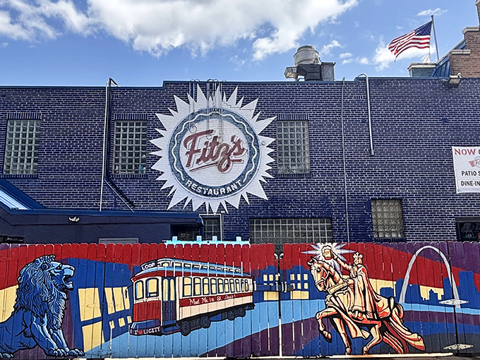 St. Louis pride shines from this vibrant mural outside Fitz's, where local landmarks frame the restaurant's signature sunburst logo against deep blue brick.