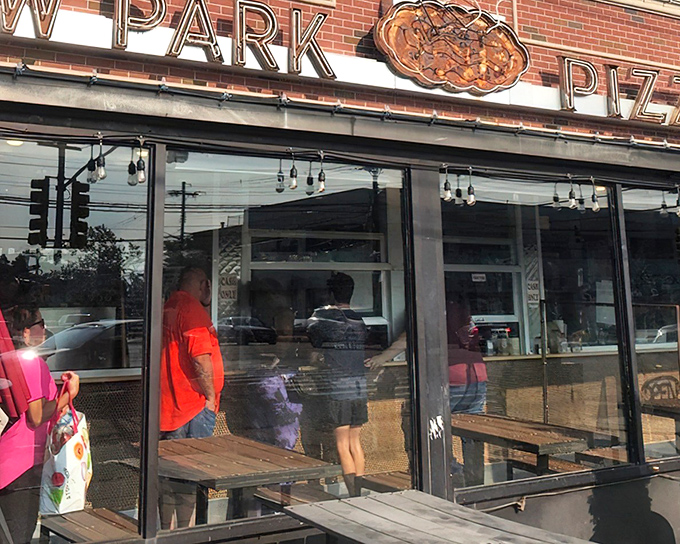 The iconic neon sign of New Park Pizza beckons hungry travelers like a lighthouse guiding ships to safe harbor. Pizza paradise awaits.