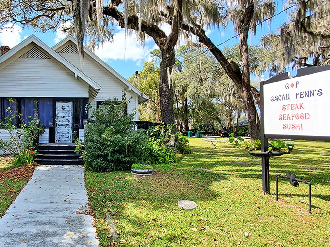 The restaurant's welcoming entrance path leads you past lush greenery to a white cottage where culinary magic awaits behind that blue door.