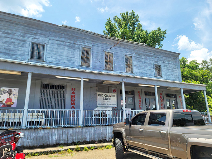The weathered blue exterior of The Old Country Store stands like a culinary time machine, promising Southern treasures to those wise enough to stop.