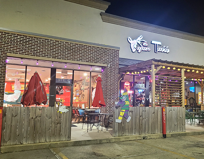 The neon crawfish sign beckons like a lighthouse for hungry souls. String lights and wooden fencing create that "come as you are" vibe that promises authentic Cajun comfort.