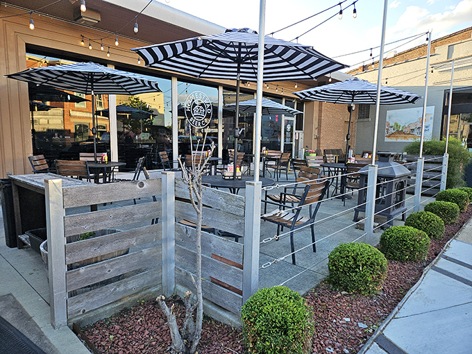 The patio at Homestead Taproom beckons with striped umbrellas and rustic wooden dividers, creating an urban oasis perfect for pizza-fueled conversations.
