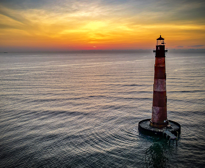 Golden hour transforms this maritime guardian into a postcard-perfect silhouette. Mother Nature showing off her lighting skills again.