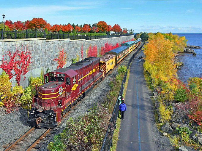 Fall's fiery palette creates nature's perfect backdrop as the maroon locomotive glides between Lake Superior and a canopy of autumn splendor.