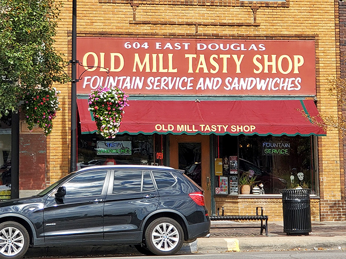 The iconic red awning of Old Mill Tasty Shop beckons like a culinary lighthouse, promising comfort food treasures within downtown Wichita's bustling streets.