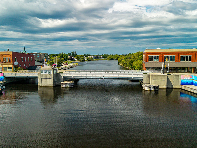 The Thunder Bay River cuts through downtown Alpena like nature's main street, with the drawbridge connecting the city's historic halves under Michigan's ever-dramatic skies.