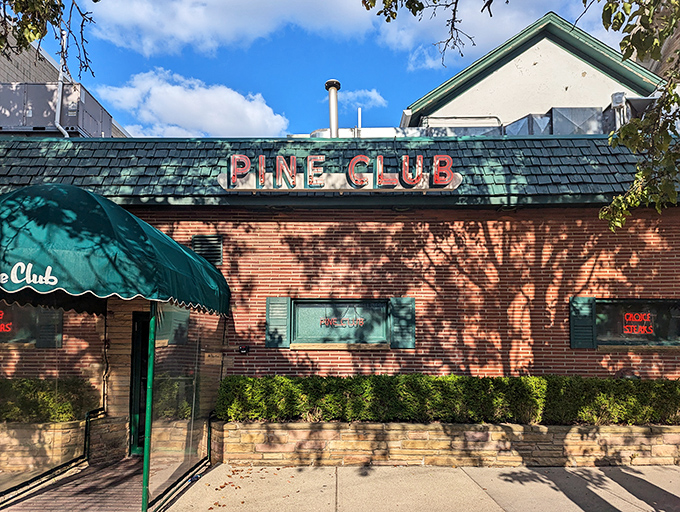 Modest brick, green awnings, and that glowing "PRIME STEAKS" window sign – The Pine Club's unassuming facade gives no hint of the culinary magic happening inside.