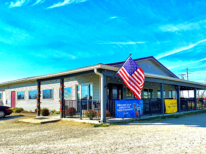 The American flag waves proudly outside 73 Grill, a humble roadside haven where culinary treasures await behind that unassuming beige exterior.