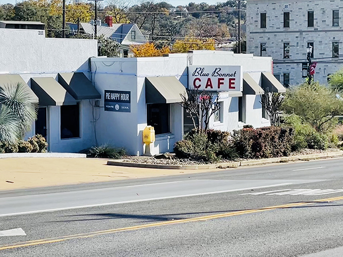 The unassuming white exterior of Blue Bonnet Cafe stands like a culinary lighthouse on Highway 281, beckoning hungry travelers with its blue-striped awnings and timeless charm.