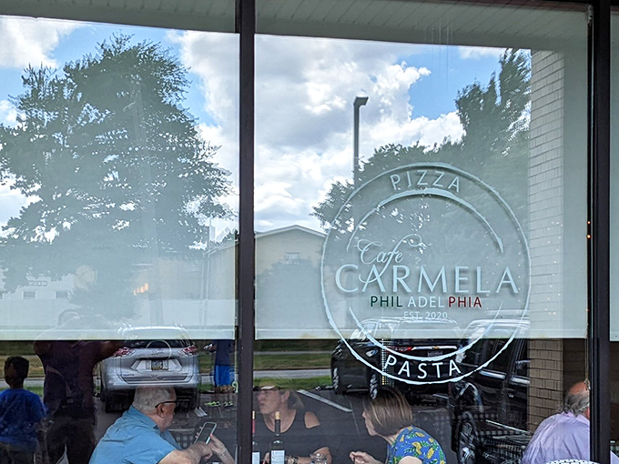 The elegant window emblem of Cafe Carmela beckons hungry travelers with promises of Italian perfection beyond the glass.