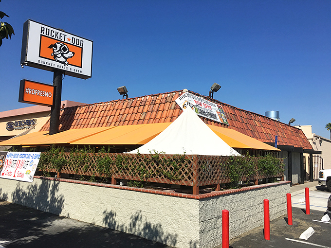The unassuming exterior with its distinctive red-tiled roof might fool you, but inside awaits a temple to tubular meat excellence that will change your hot dog standards forever.