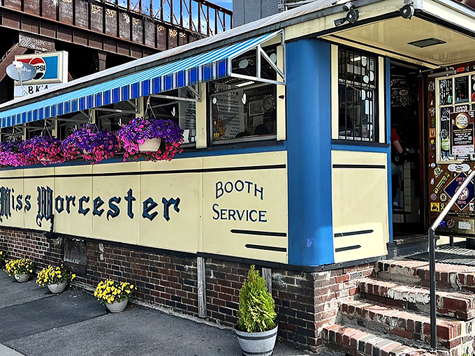 The iconic blue and cream exterior of Miss Worcester Diner stands proudly like a time capsule, complete with vintage "BOOTH SERVICE" lettering and vibrant flower boxes.