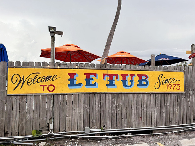 The unassuming wooden fence with its cheerful yellow "Welcome to Le Tub" sign is like a secret password to burger paradise.