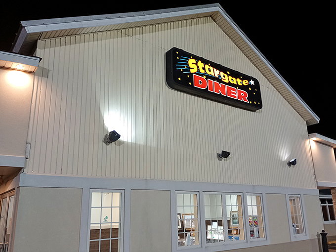 By night, the illuminated Stargate Diner sign becomes a beacon for hungry travelers seeking comfort food that transcends ordinary diner fare.