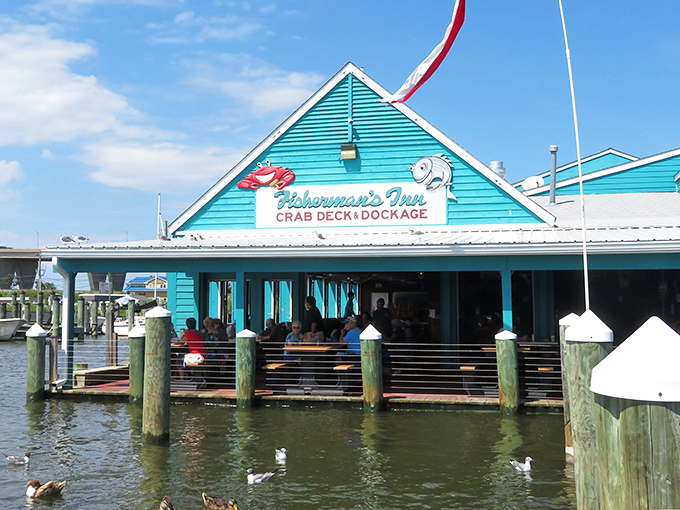 The turquoise beacon of seafood paradise sits proudly on the water, where ducks gather like eager food critics waiting for the day's special.