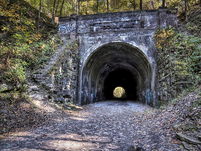 The entrance to Moonville Tunnel stands like a portal to another era, its weathered stone arch framing the darkness beyond with haunting beauty.