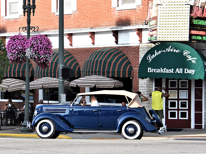 Classic Americana meets breakfast heaven &ndash; a vintage convertible cruises past Lake Aire's inviting green awnings and vibrant hanging flower baskets, promising comfort food and small-town charm.