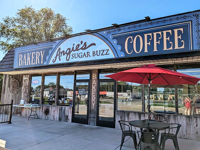 The blue and white storefront of Angie's Sugar Buzz beckons like a sugar-laden lighthouse, complete with cheerful red umbrellas for outdoor indulgers.