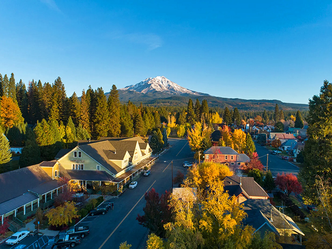 Mount Shasta stands sentinel over McCloud like a protective parent, its snow-capped peak gleaming in the autumn sunshine while colorful trees frame the historic downtown.