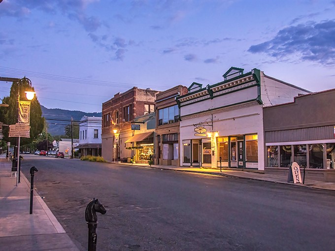 Twilight transforms Miner Street into a scene from a nostalgic postcard, where historic buildings glow with warm light against the backdrop of Siskiyou mountains.