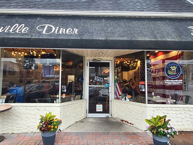 Seasonal planters flank the welcoming entrance, where an American flag hints at the classic diner experience waiting inside.