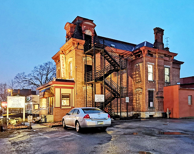 The historic brick building glows at twilight, its fire escape zigzagging dramatically against the fa&ccedil;ade like an architectural time machine waiting to transport visitors.