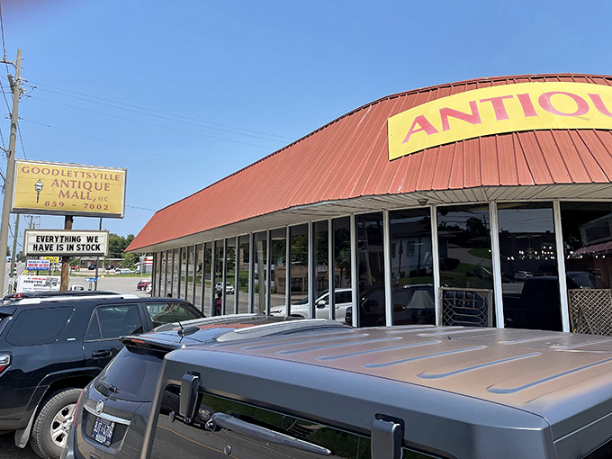 The red metal roof and yellow "ANTIQUES" sign beckon like an old friend. Stone lions stand guard, promising treasures within this unassuming brick building.