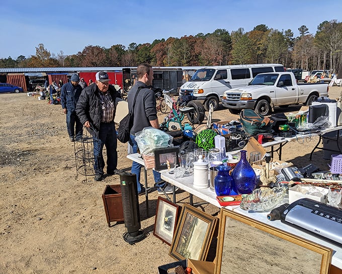 Treasure hunting in action! Shoppers browse tables laden with glassware, picture frames, and vintage finds under the clear Arkansas sky &ndash; a bargain hunter's paradise in full swing.