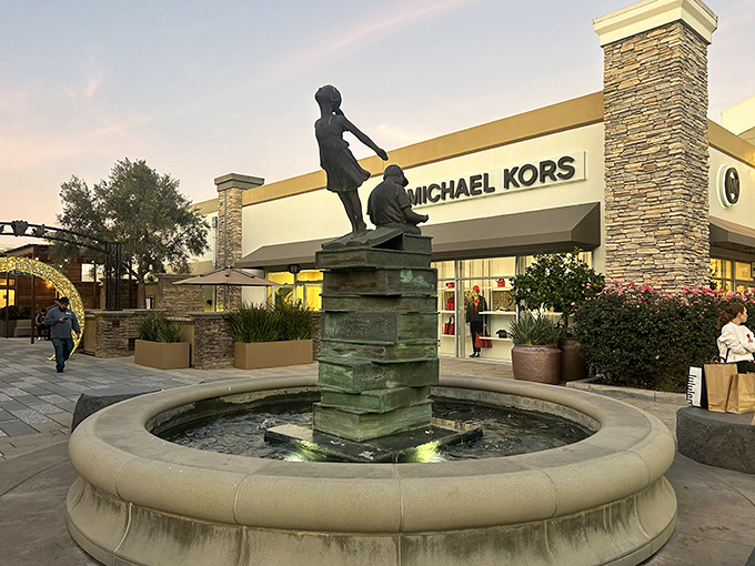 A sculptural fountain creates an upscale ambiance outside Michael Kors, proving discount shopping doesn't have to feel discount.