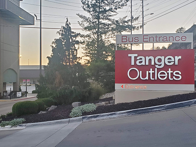The iconic red Tanger Outlets sign welcomes bargain hunters like a beacon of hope for wallets everywhere. Shopping salvation awaits just beyond those trees.