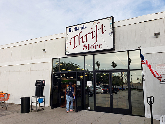 The unassuming exterior of Redlands Thrift Store - where treasure hunting begins beneath that iconic red sign.