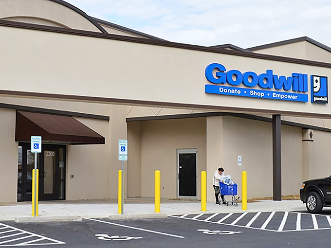 The blue Goodwill sign beckons like a lighthouse for bargain hunters. This unassuming exterior houses fashion treasures waiting to be discovered.