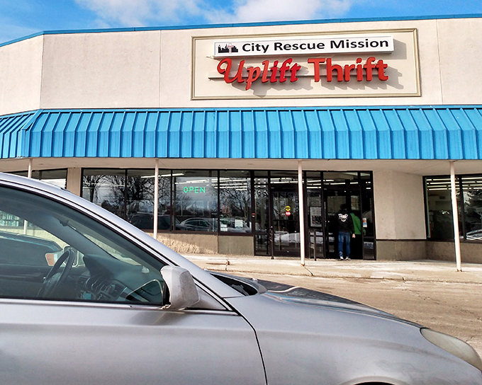 The bright blue awning of City Rescue Mission Uplift Thrift stands out like a beacon for bargain hunters, promising treasures within its unassuming exterior.