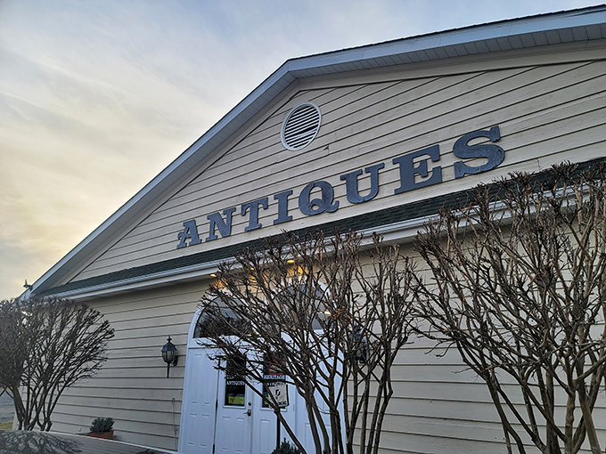 The classic white facade of Heritage Antiques Market welcomes treasure hunters with vibrant blue hydrangeas and the promise of discoveries within.
