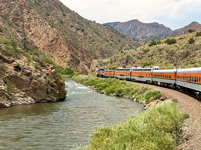 The iconic orange locomotive snakes alongside the Arkansas River, a perfect example of how Colorado casually combines engineering marvels with jaw-dropping natural beauty.