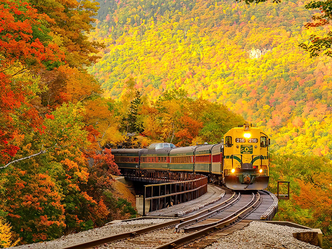 Nature's own fireworks display frames this yellow locomotive as it curves through Crawford Notch. Fall in New Hampshire isn't just a season—it's a spectacular show.