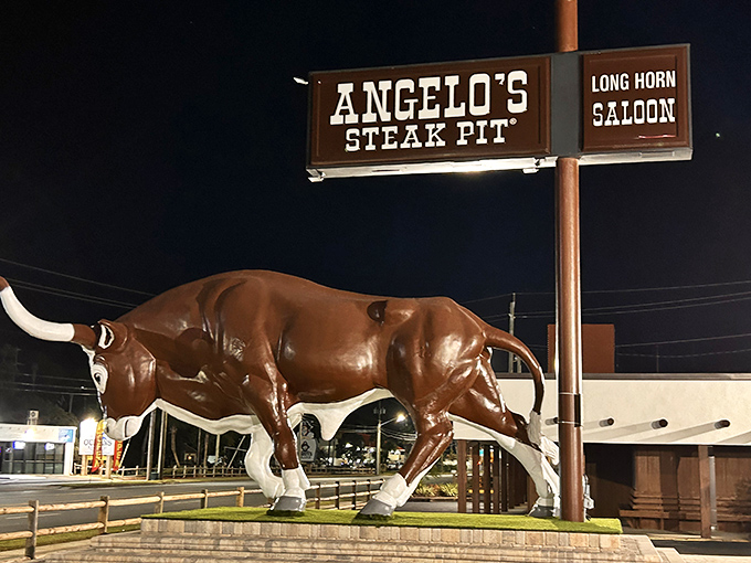 Big Gus stands guard outside Angelo's Steak Pit, a fiberglass sentinel promising carnivorous delights within. At night, he's even more impressive.