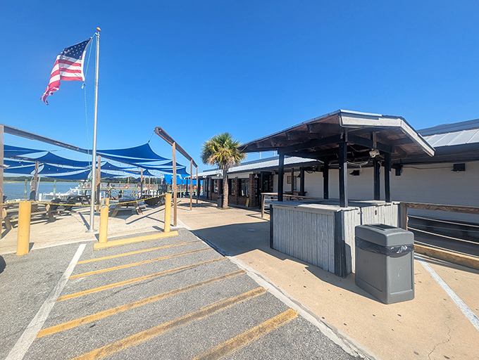 The American flag waves proudly over Hudson's outdoor seating area, where blue canopies provide shade for diners enjoying seafood with a side of patriotism.