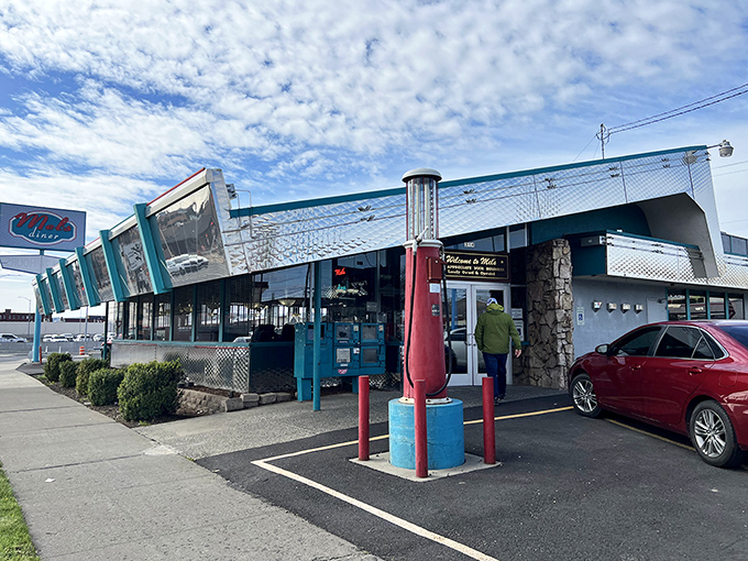 The gleaming chrome exterior of Mel's Diner shines like a beacon of breakfast hope, complete with vintage gas pump standing guard.