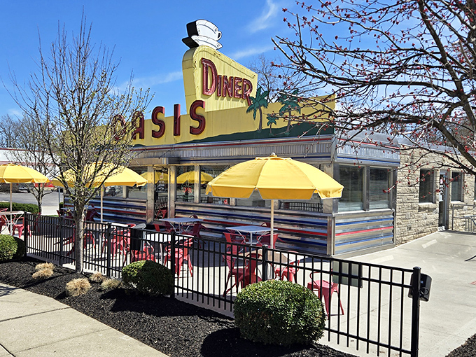 The gleaming yellow and chrome exterior of Oasis Diner stands like a time capsule on Plainfield's main drag, complete with those cheerful umbrellas promising shade and satisfaction.
