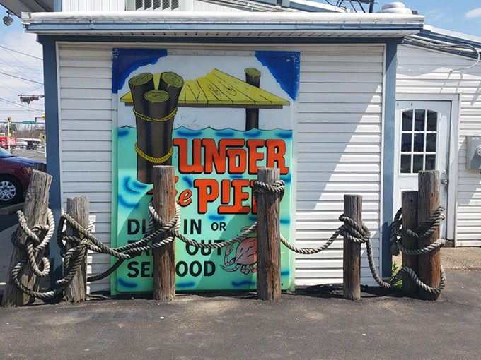 The unassuming exterior of Under the Pier, where nautical posts and ropes set the stage for seafood magic hiding behind that colorful mural.