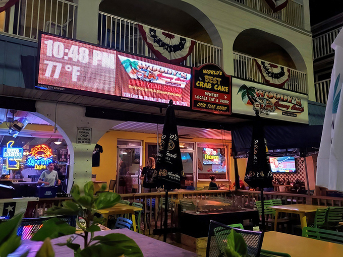As night falls, Woody's lights up the Dewey Beach scene, proudly advertising its famous crab cakes while beckoning hungry visitors with its warm glow.
